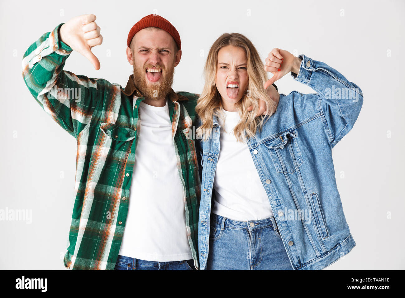 Portrait of an angry young stylish couple standing isolated over white ...