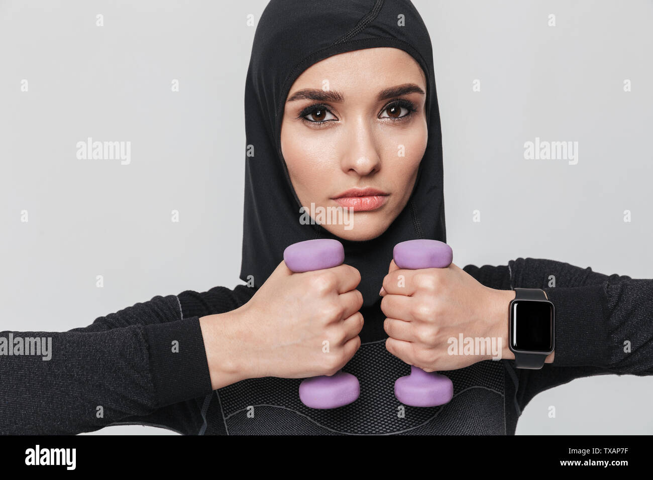 Image of young woman fitness muslim make exercises with dumbbells ...