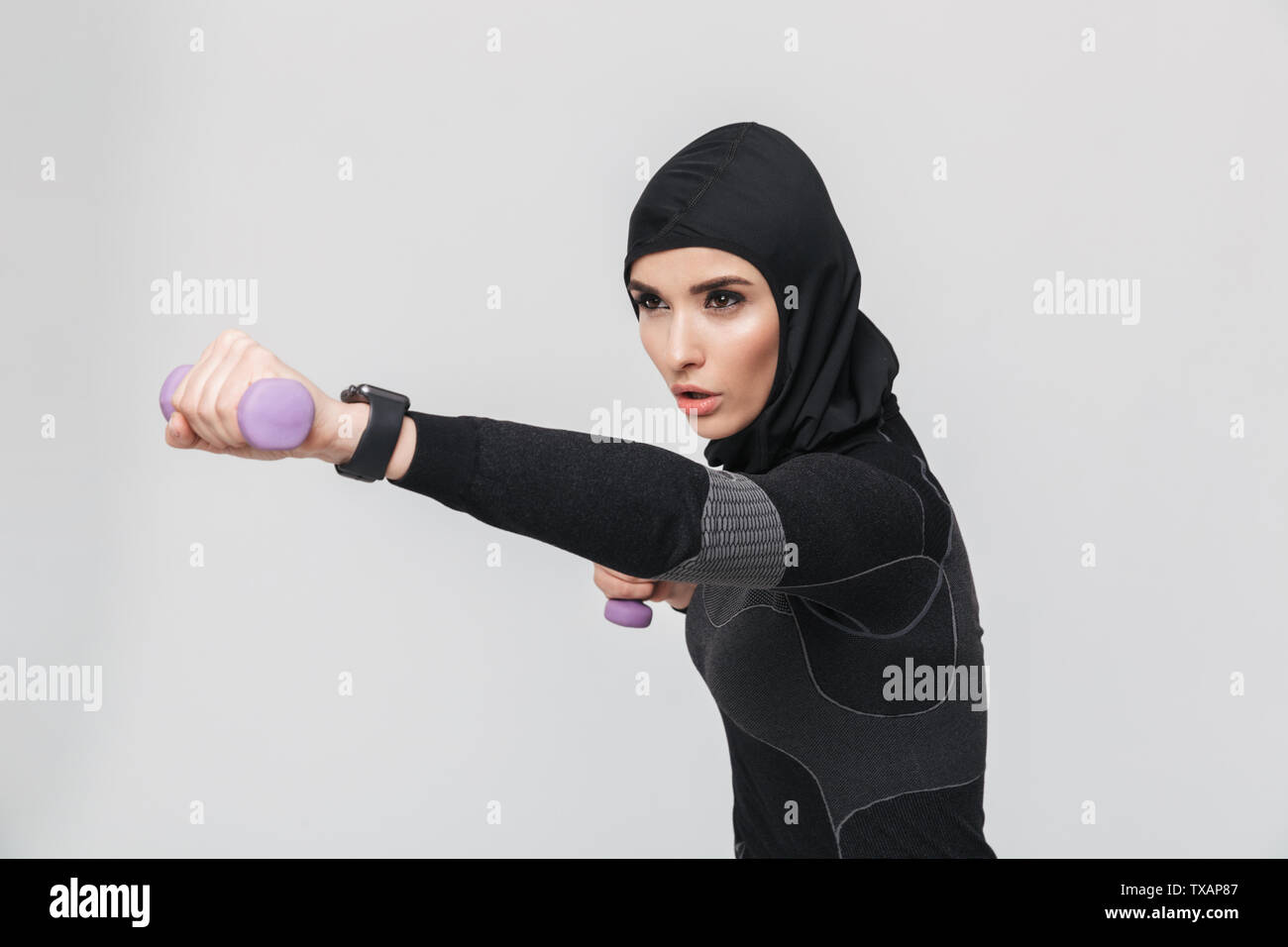 Image of young woman fitness muslim make exercises with dumbbells ...