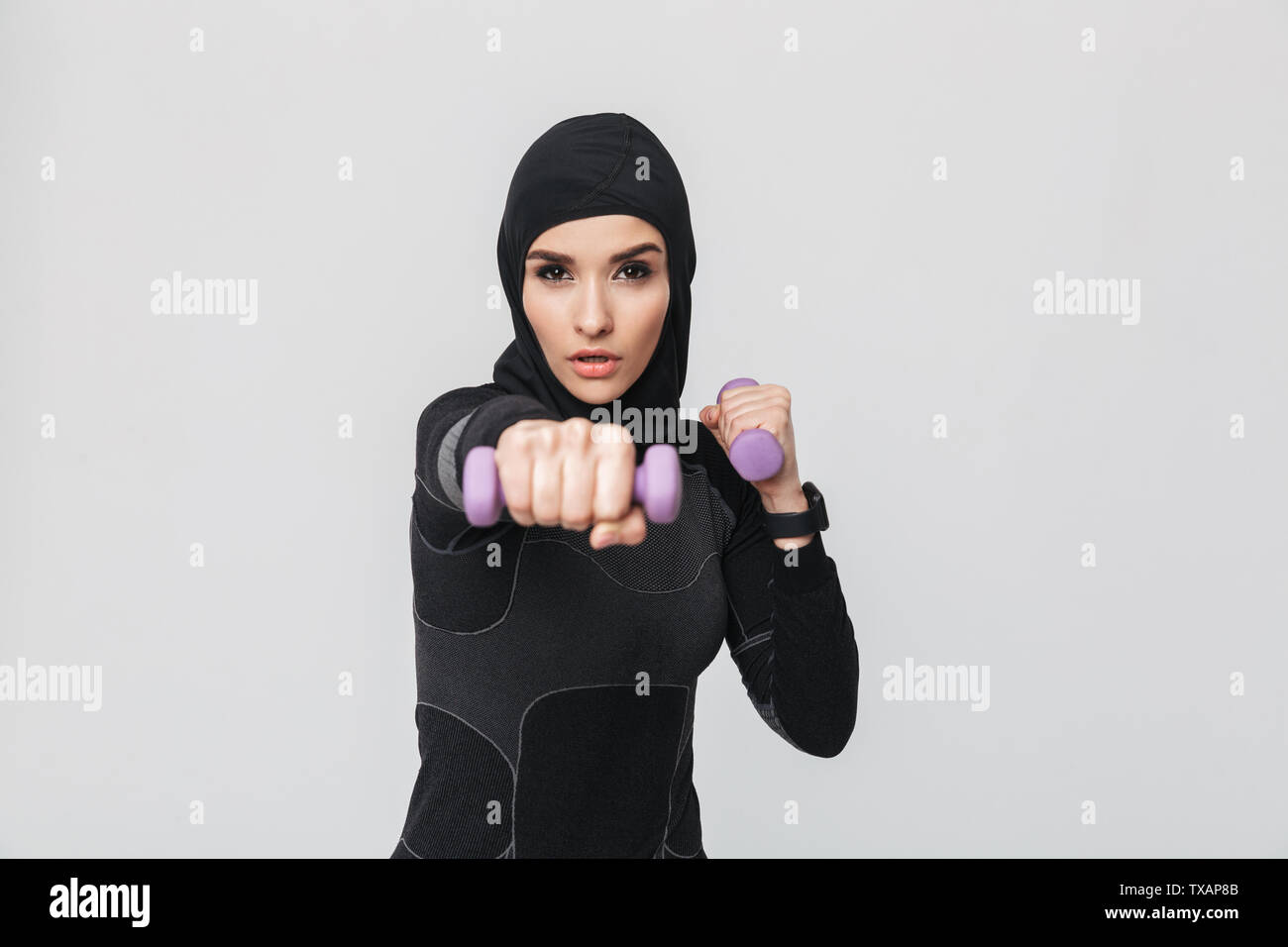 Image of young woman fitness muslim make exercises with dumbbells ...