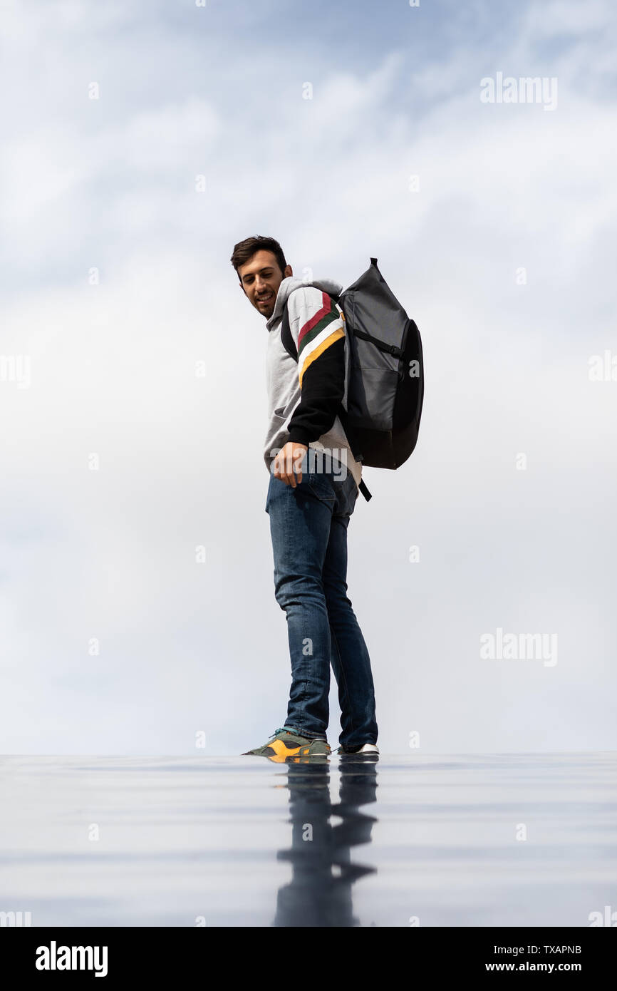 Young male standing, looking with a reflective attitude towards the ...