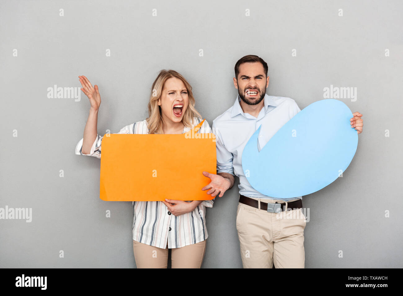 Attractive angry young couple standing isolated over gray background ...