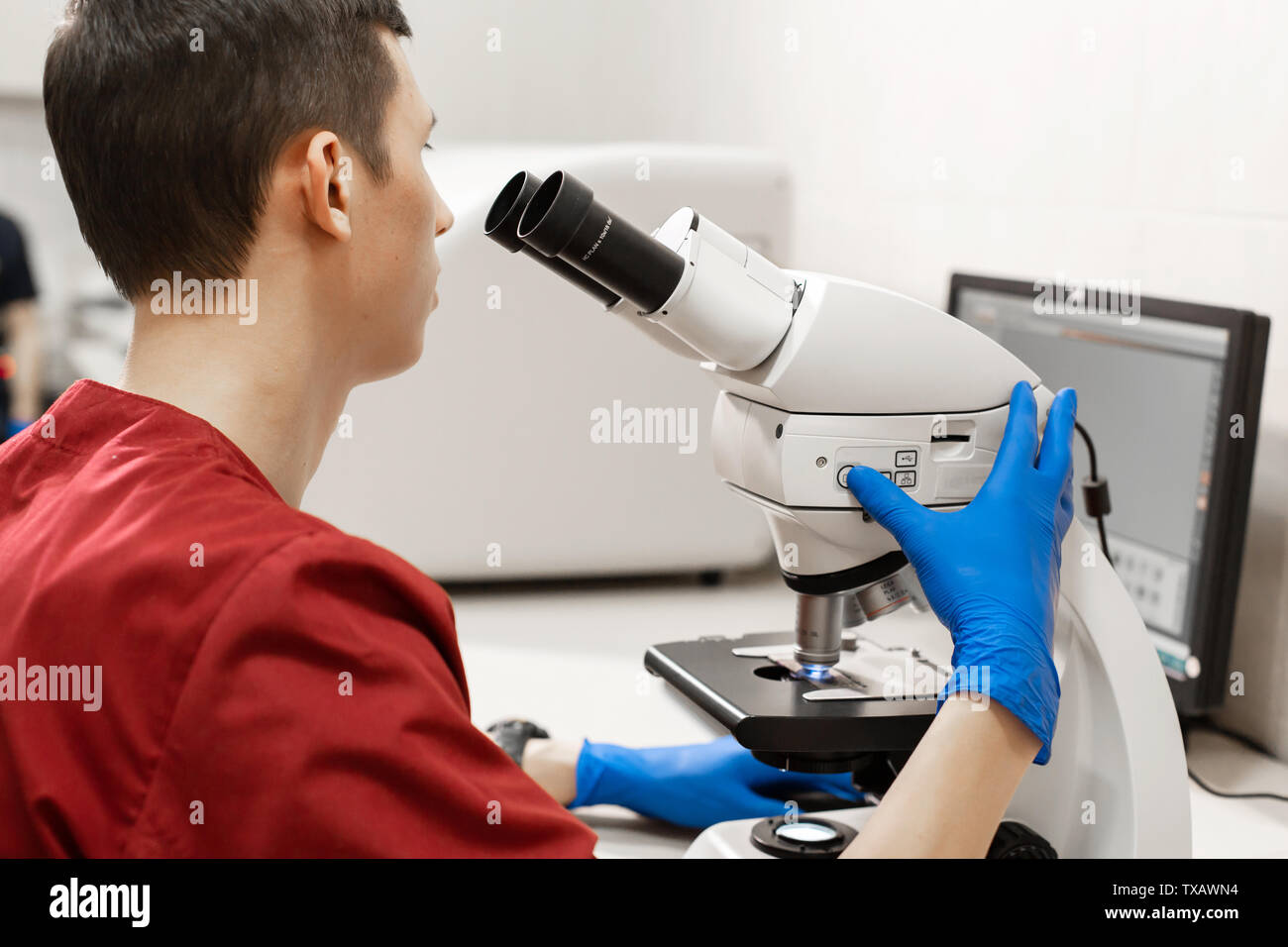 Young scientist looking through a microscope in a laboratory. Young ...