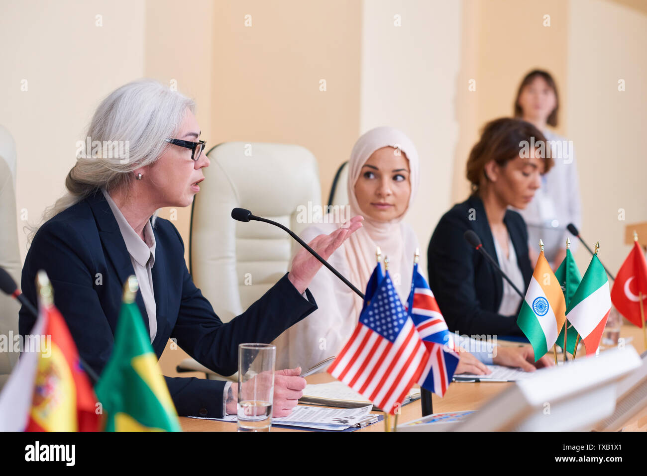 Mature confident female speaker in elegant suit explaining her opinion ...