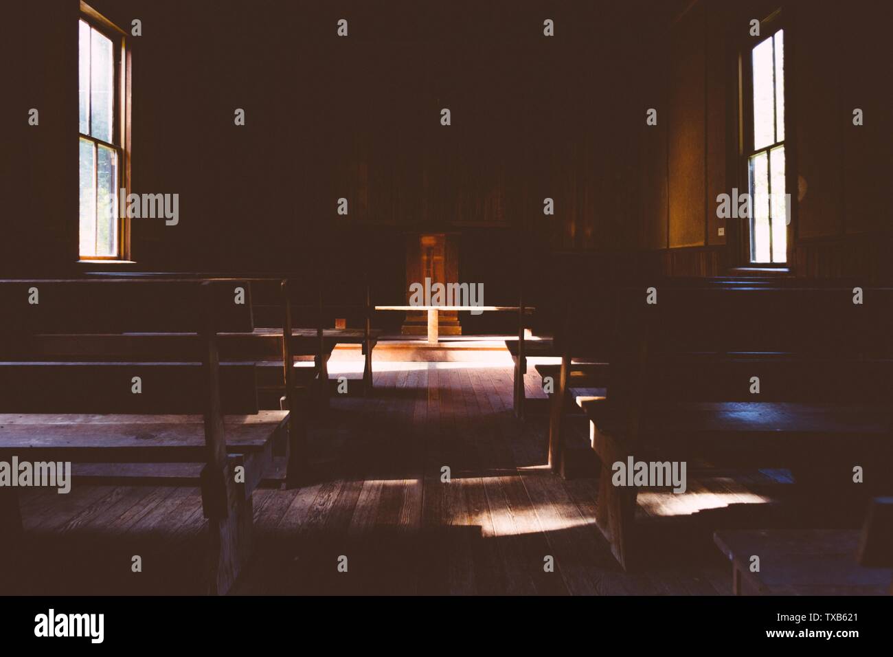 Interior of a dark wooden Christian church with a cross on the stand in ...