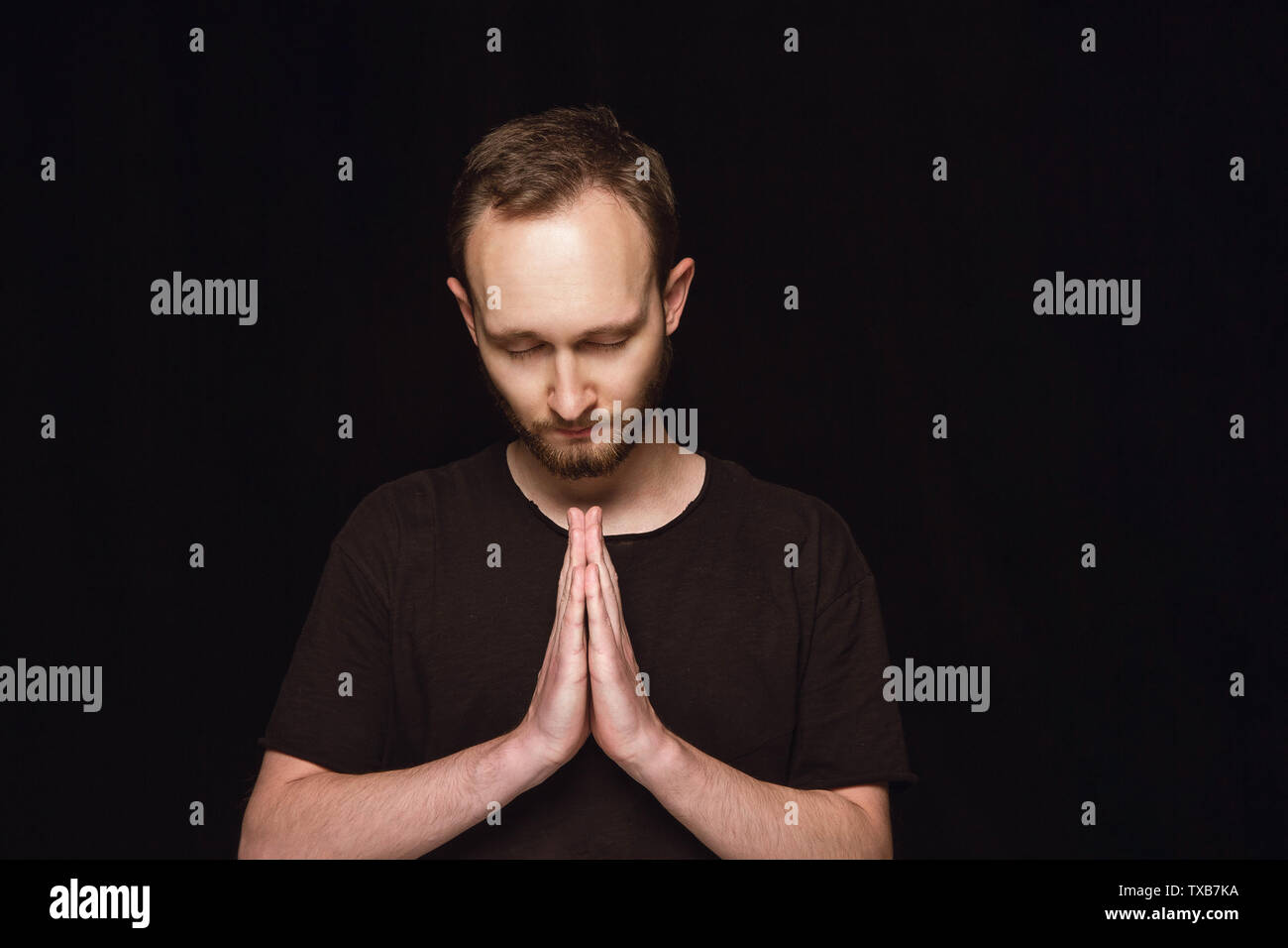 Close up portrait of young man isolated on black studio background ...