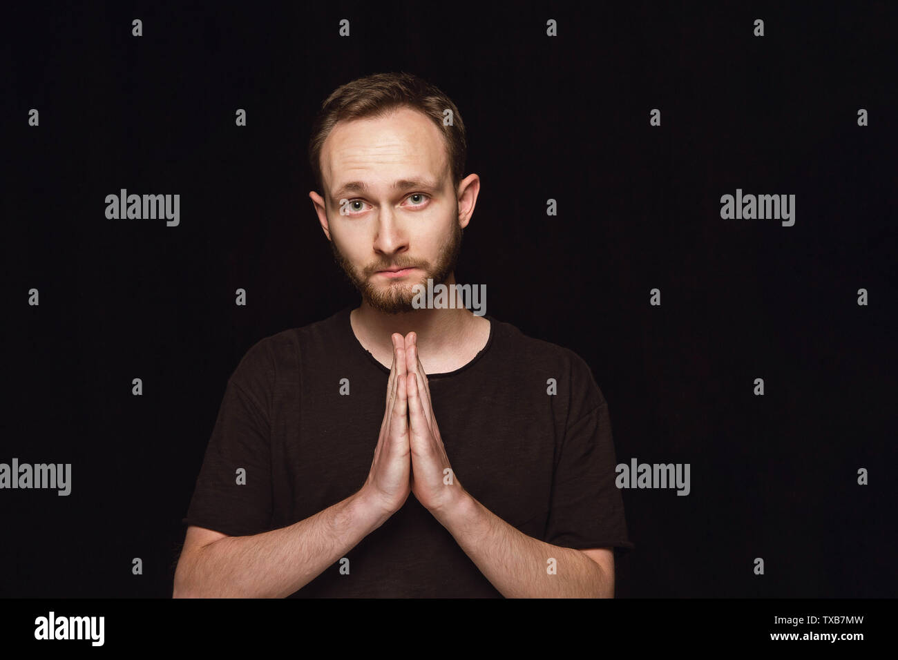 Close up portrait of young man isolated on black studio background ...
