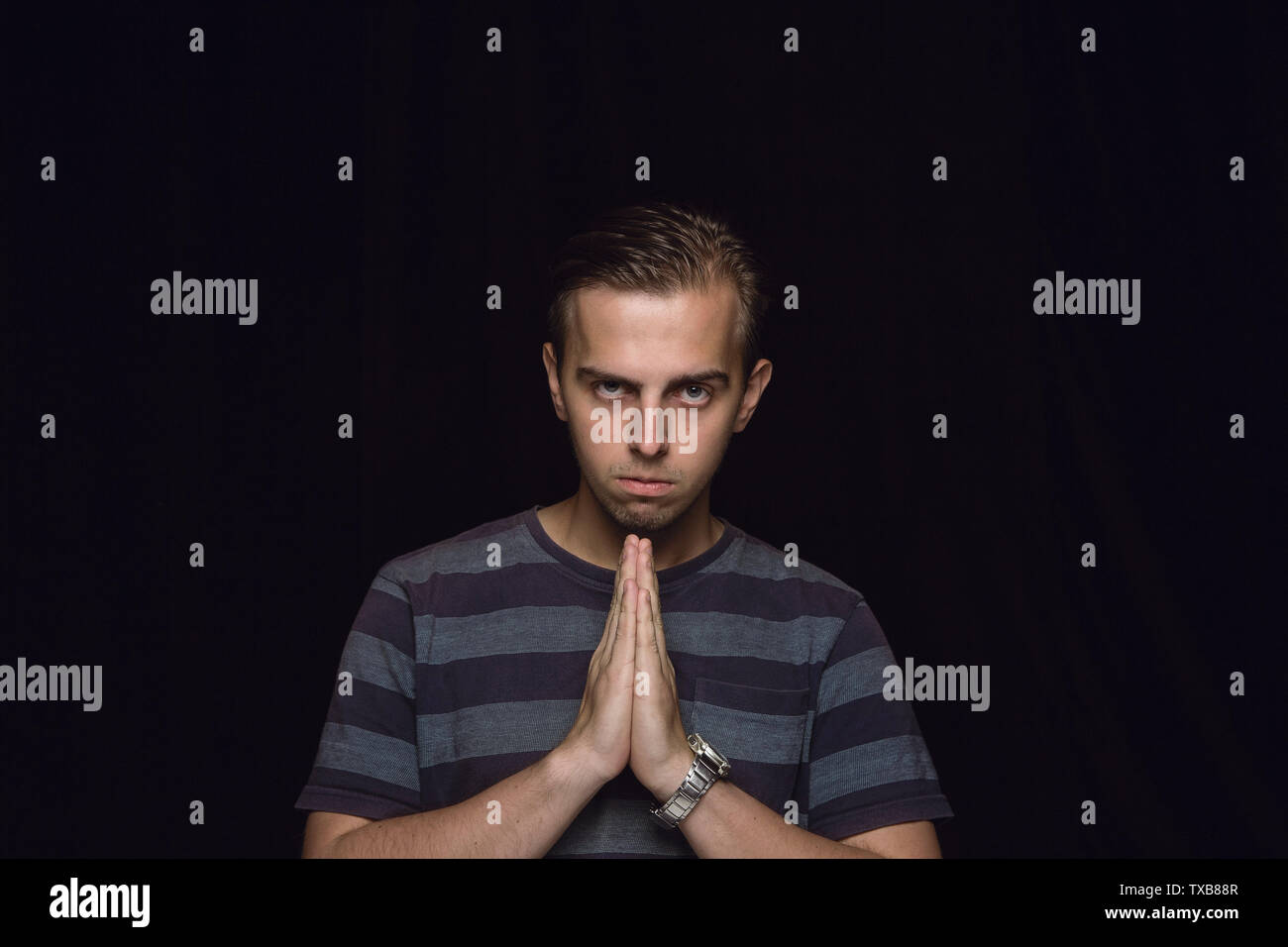 Close up portrait of young man isolated on black studio background ...
