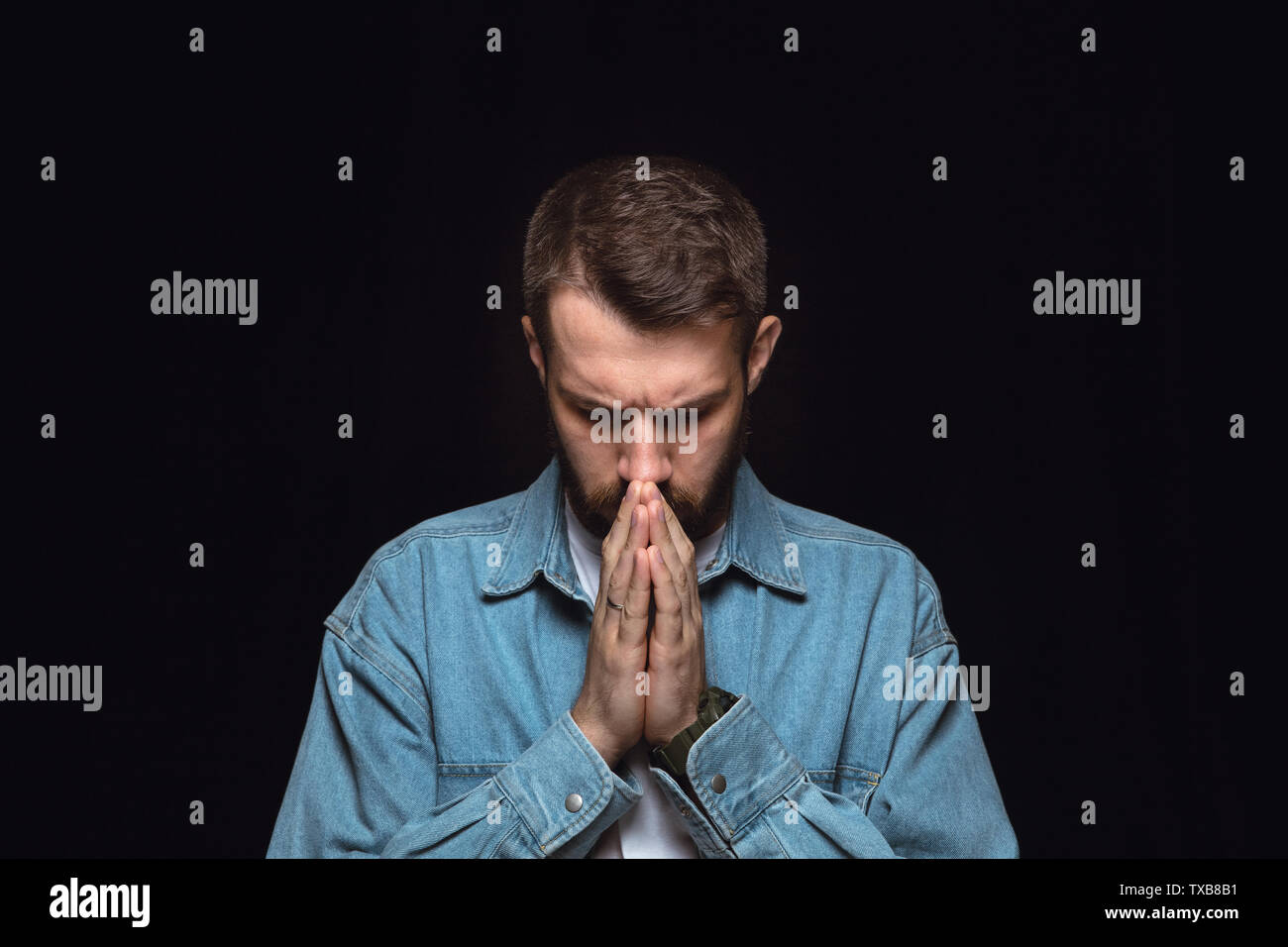 Close up portrait of young man isolated on black studio background ...