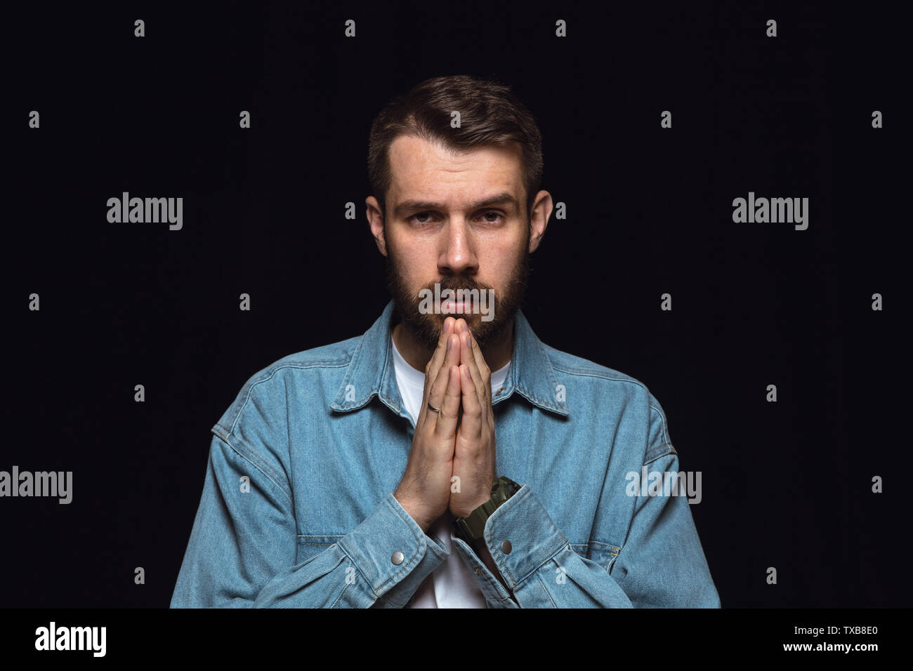 Close up portrait of young man isolated on black studio background ...
