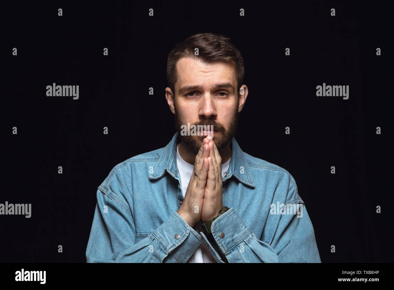 Close up portrait of young man isolated on black studio background ...
