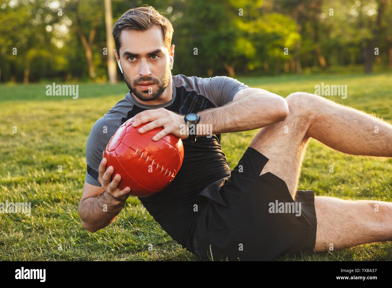 Image of a handsome young strong sports man posing outdoors at the ...