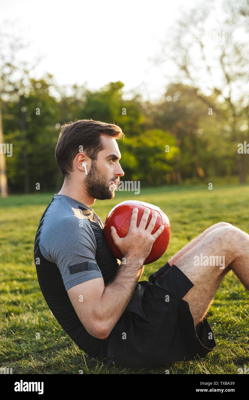 Image of a handsome young strong sports man posing outdoors at the ...