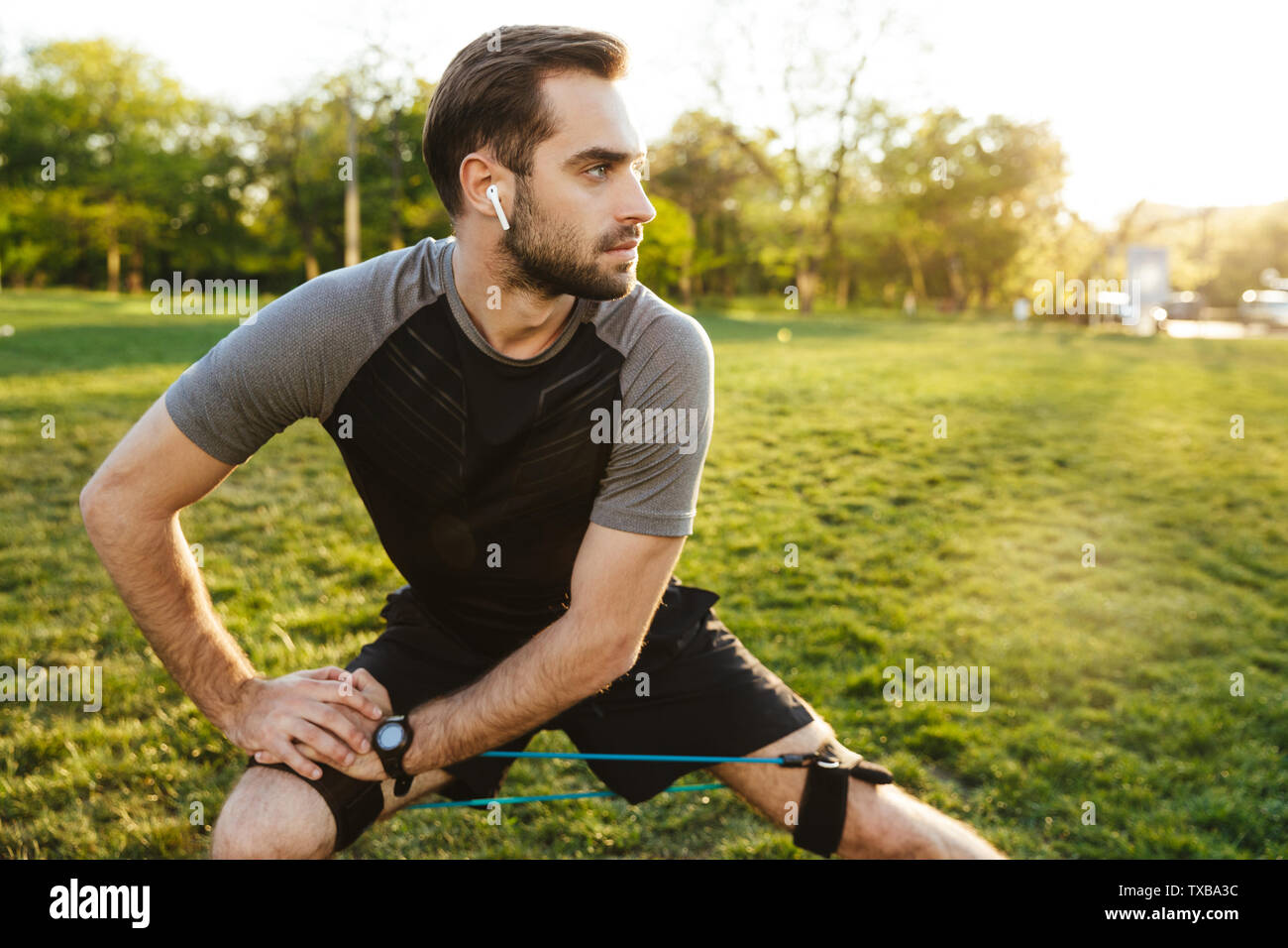 Portrait of masculine sporty man with fitness body stretching his body ...