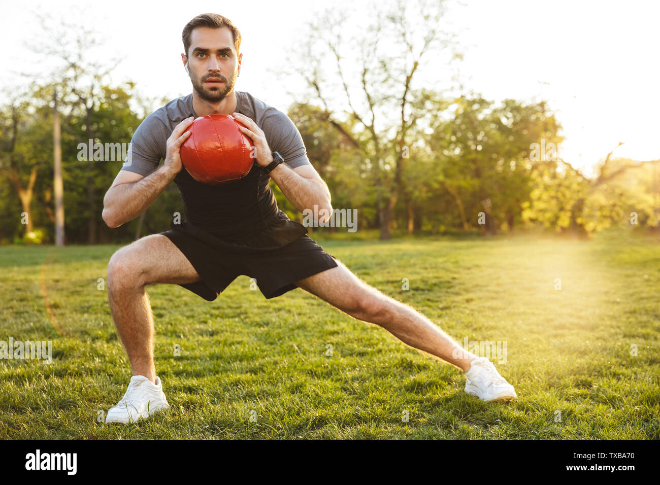 Image of a handsome young strong sports man posing outdoors at the ...