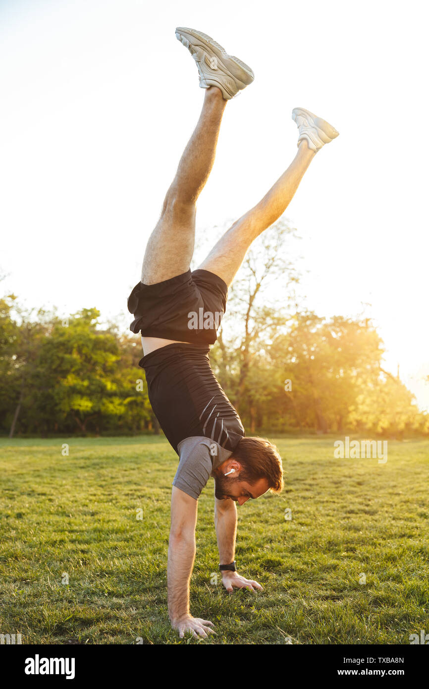 Image of a handsome young strong sports man posing outdoors at the ...
