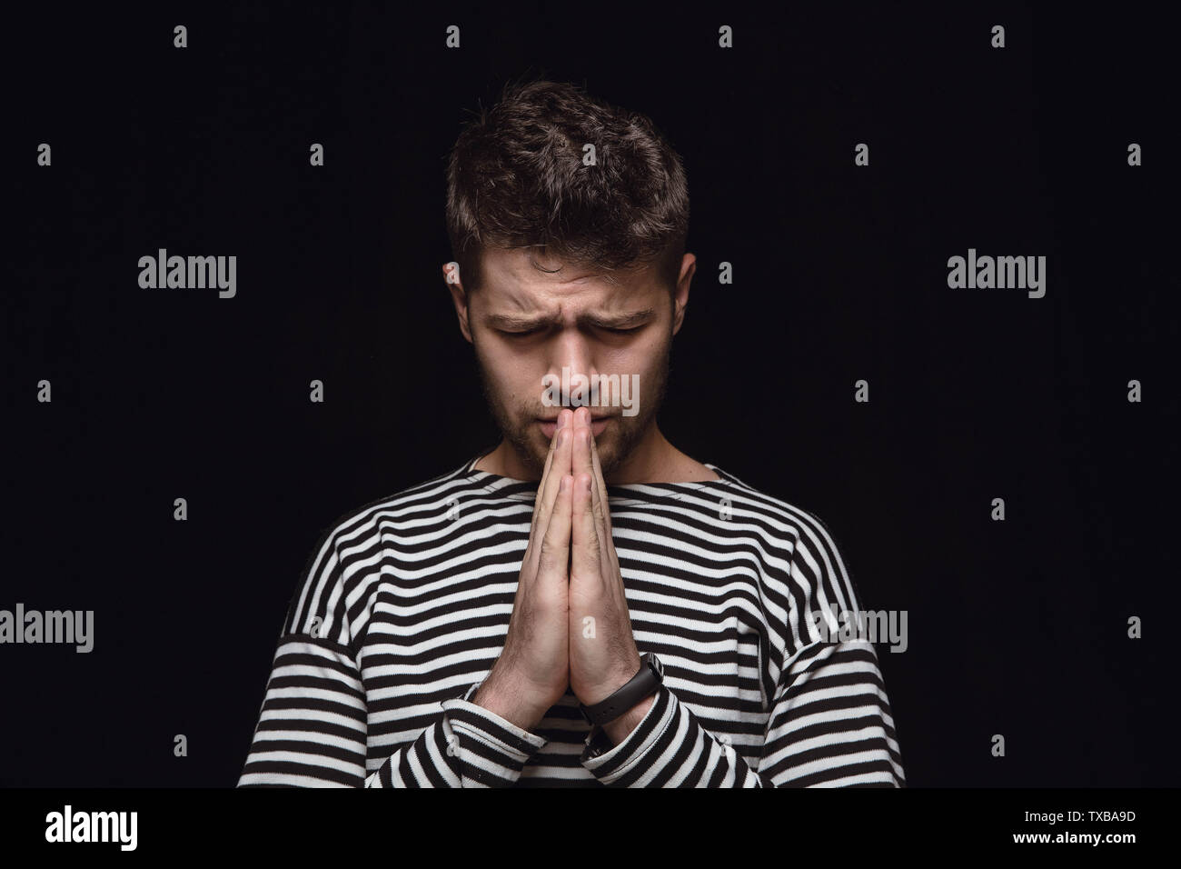 Close up portrait of young man isolated on black studio background ...