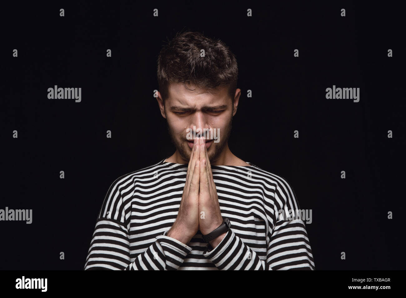 Close up portrait of young man isolated on black studio background ...
