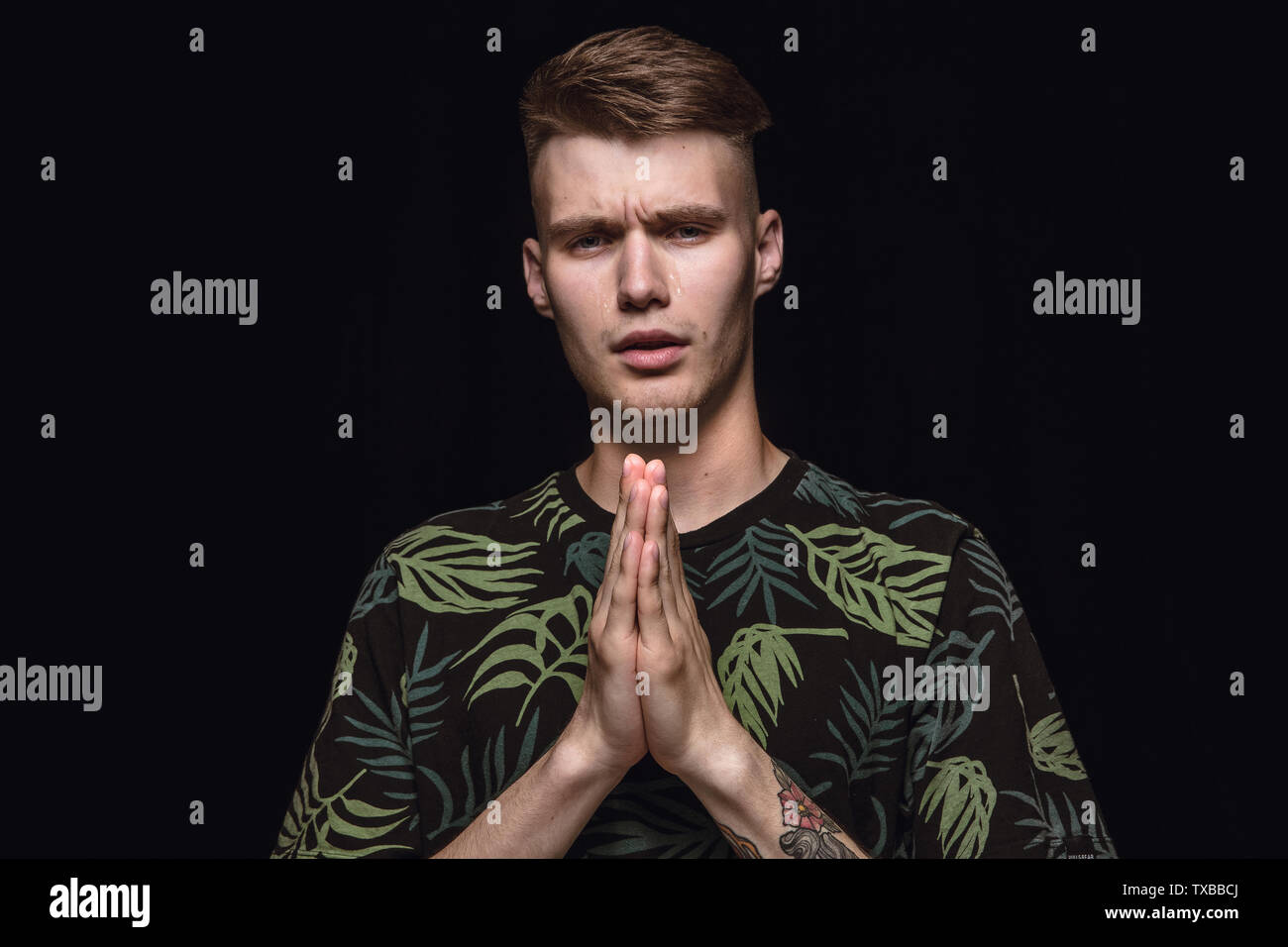 Close up portrait of young man isolated on black studio background ...
