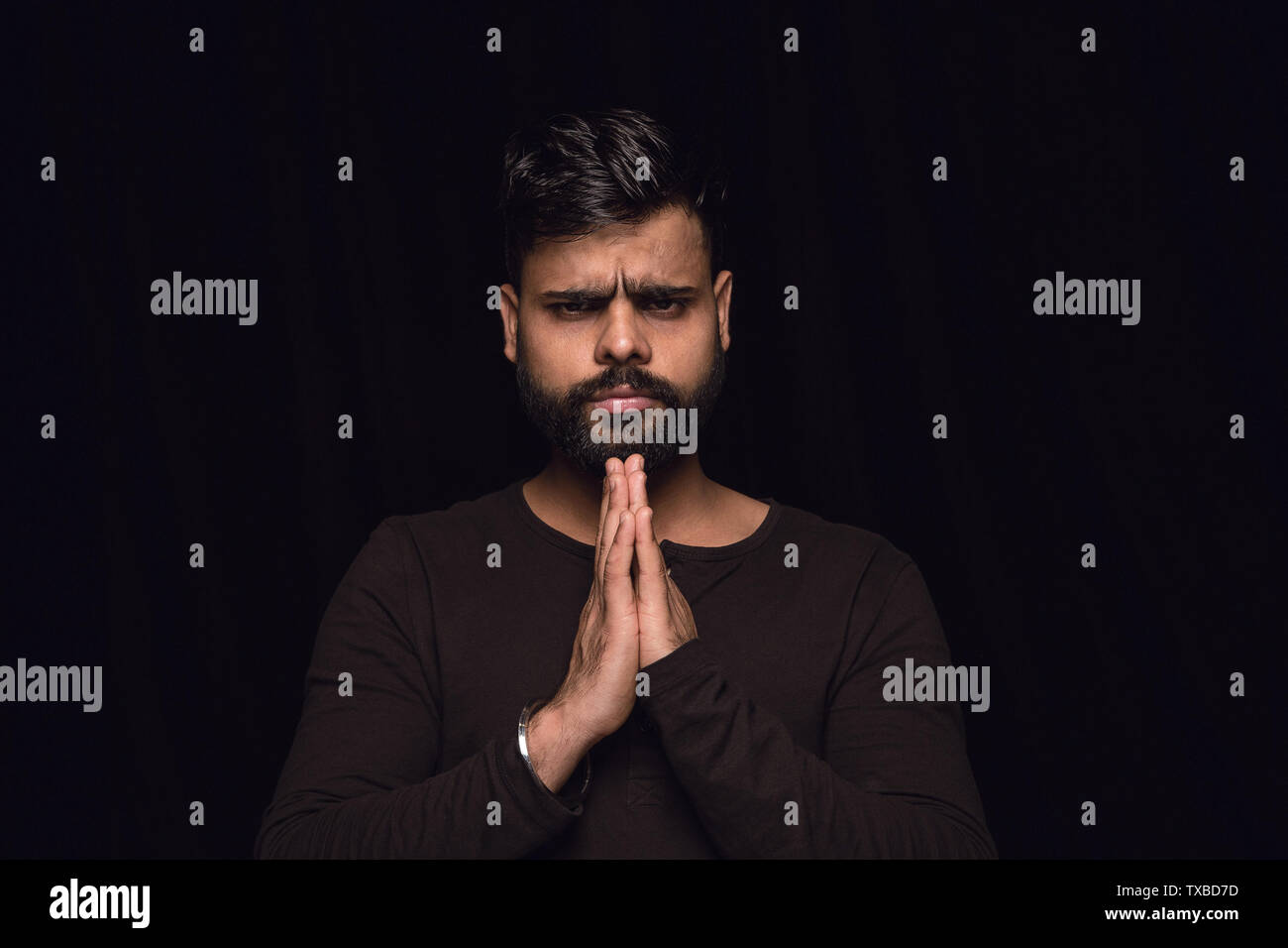 Close up portrait of young man isolated on black studio background ...