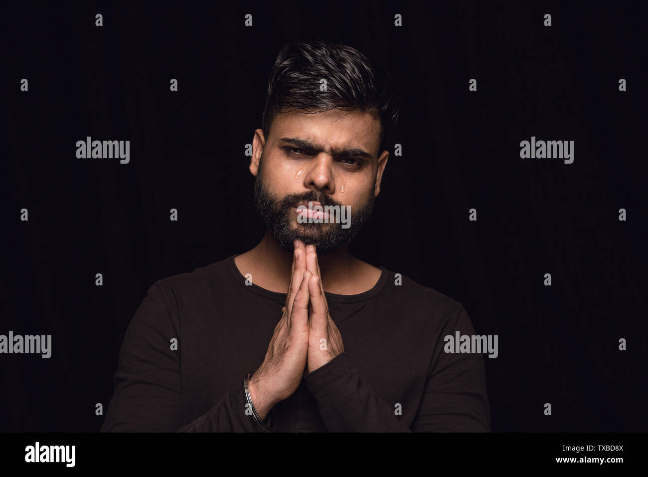 Close up portrait of young man isolated on black studio background ...