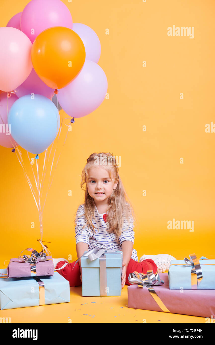 Little casual cutie with gift posing on yellow background Stock Photo ...