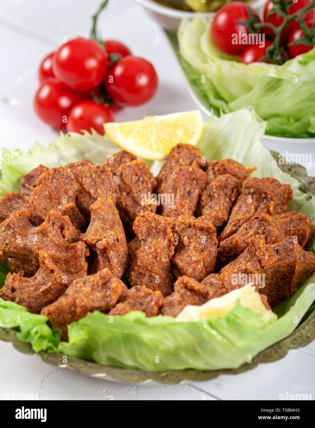 Turkish Food Cig Kofte with lemon, lettuce and parsley on silver plate ...