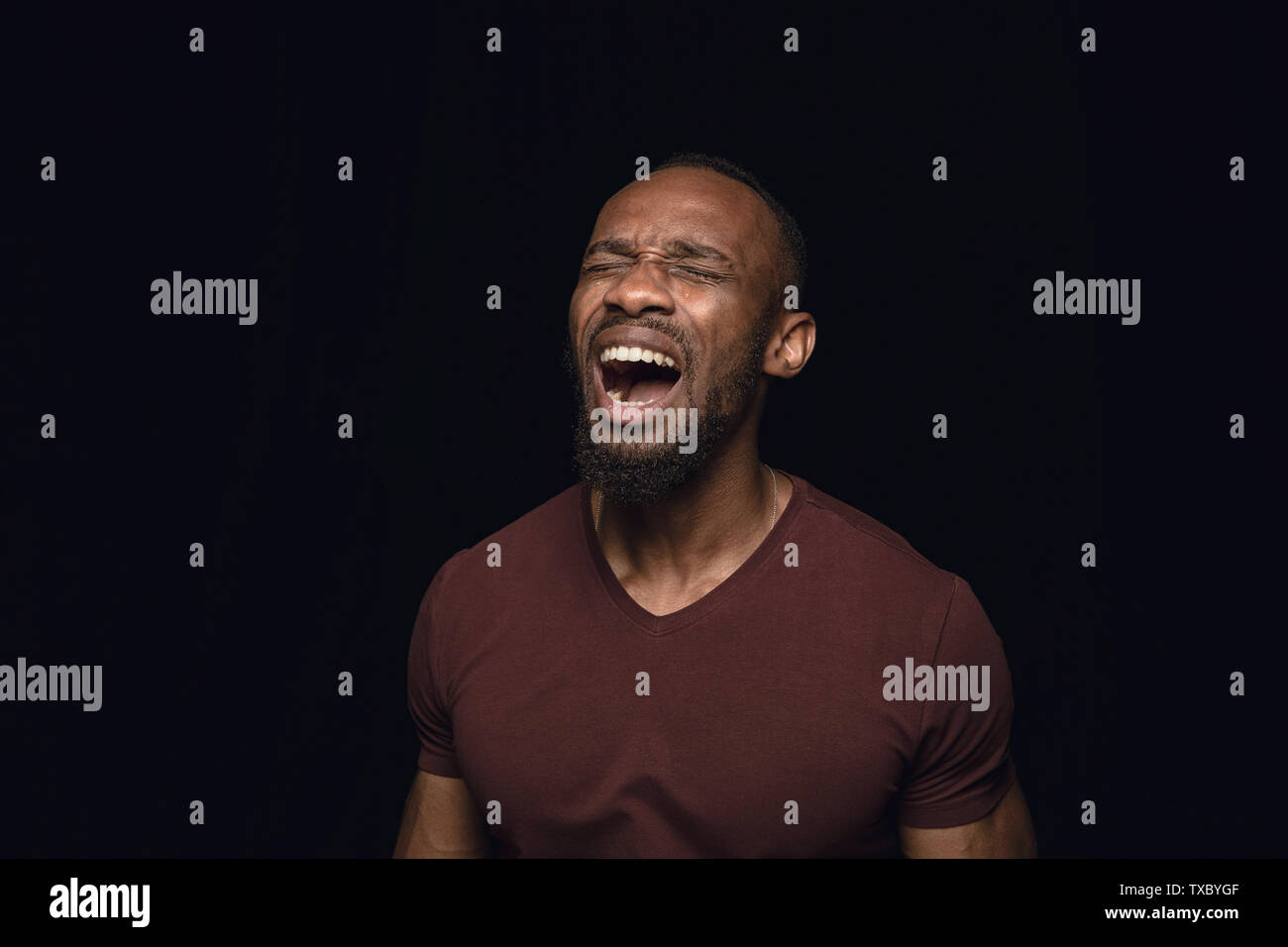 Close up portrait of young man isolated on black studio background ...