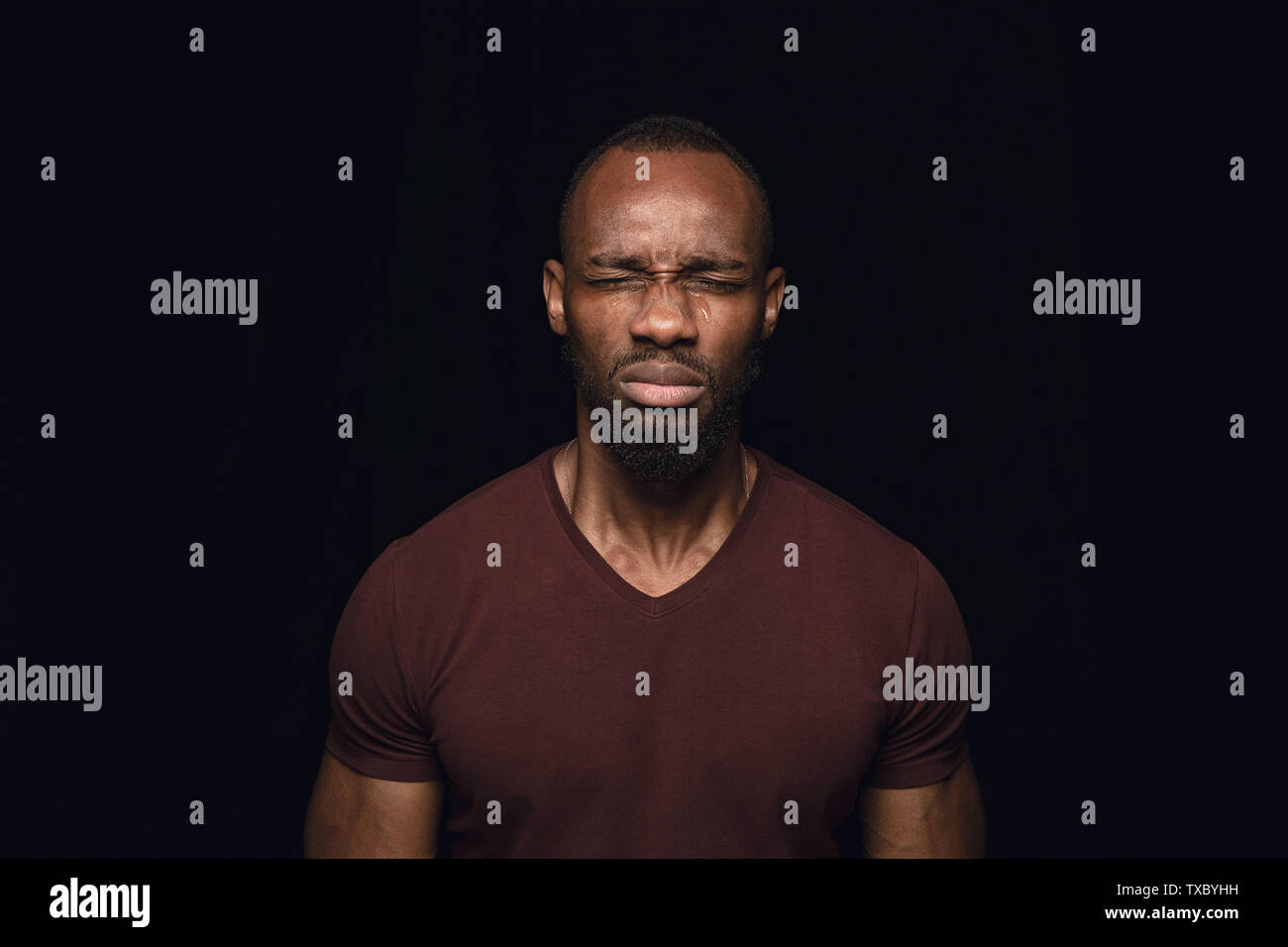 Close up portrait of young man isolated on black studio background ...
