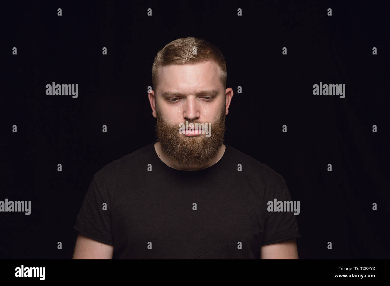 Close up portrait of young man isolated on black studio background ...
