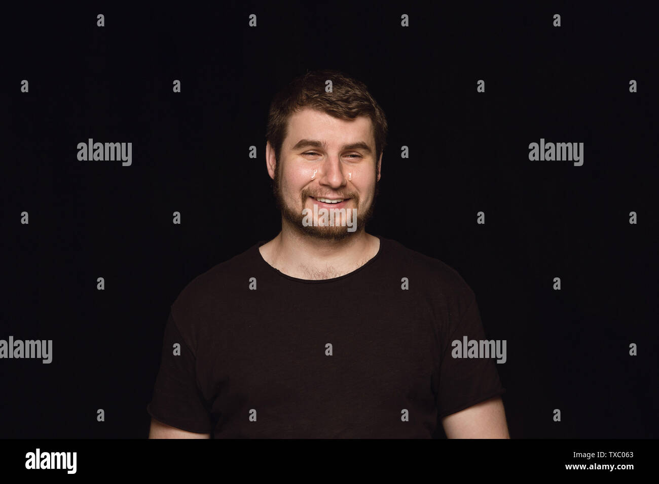 Close up portrait of young man isolated on black studio background ...