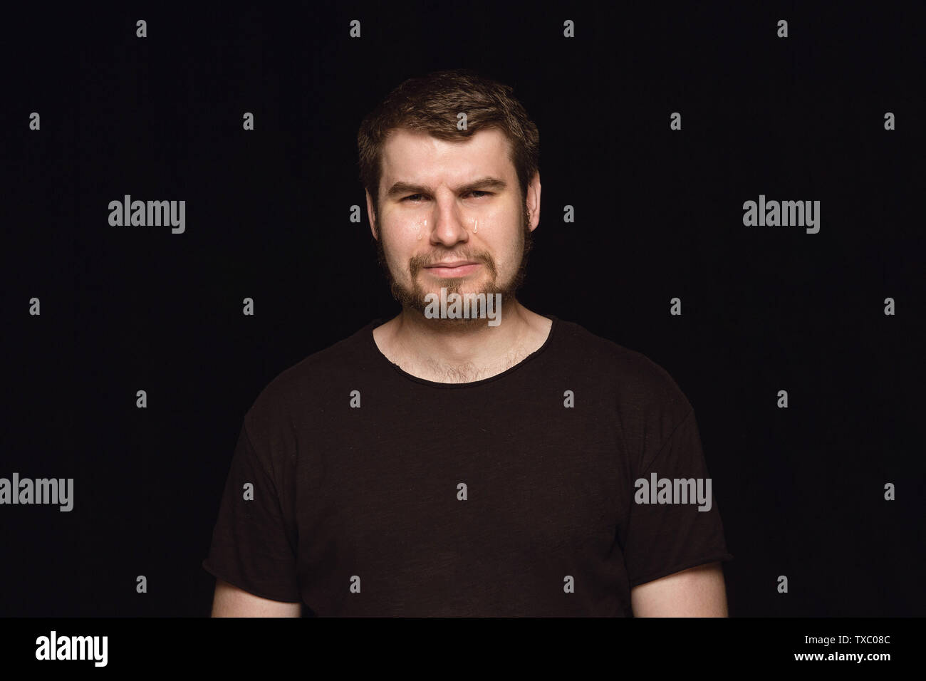 Close up portrait of young man isolated on black studio background ...