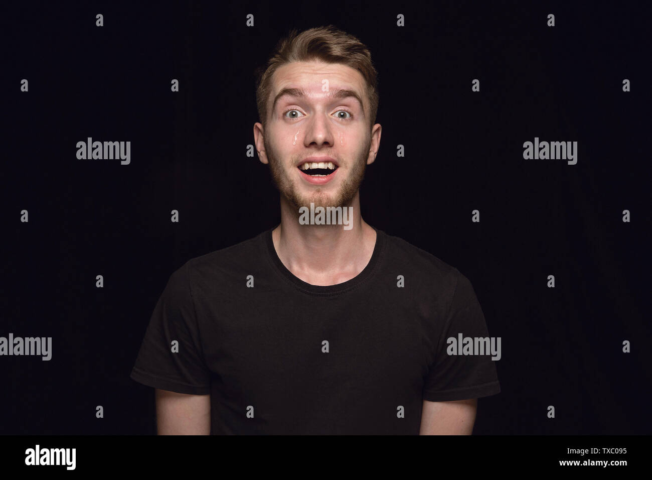 Close up portrait of young man isolated on black studio background ...