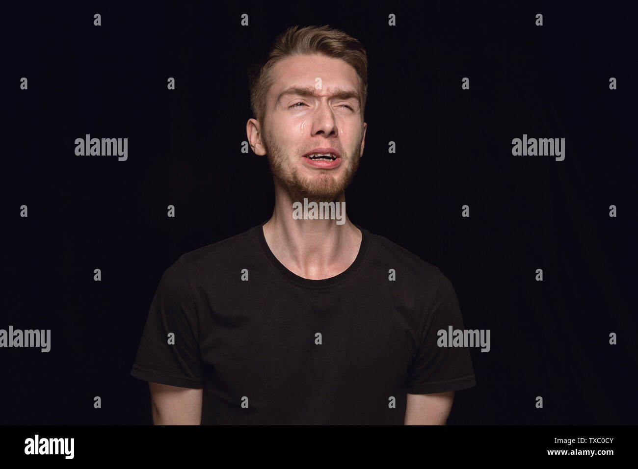 Close up portrait of young man isolated on black studio background ...