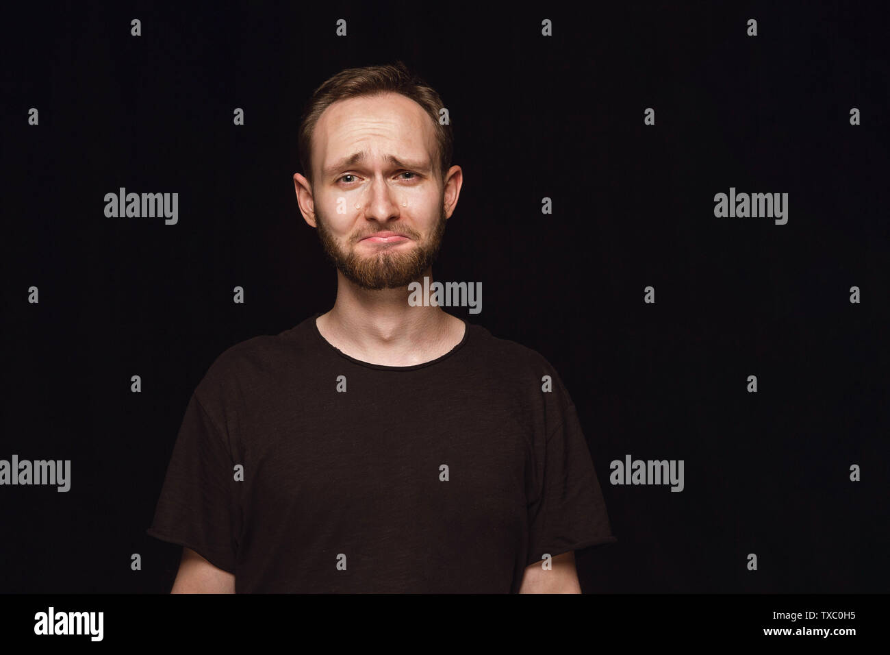 Close up portrait of young man isolated on black studio background ...