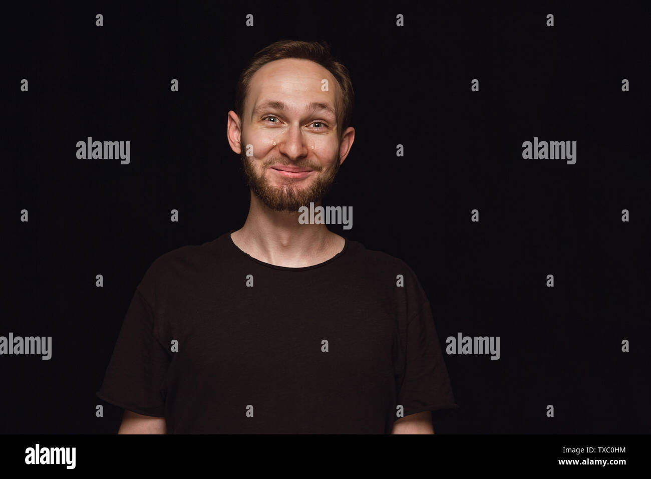 Close up portrait of young man isolated on black studio background ...