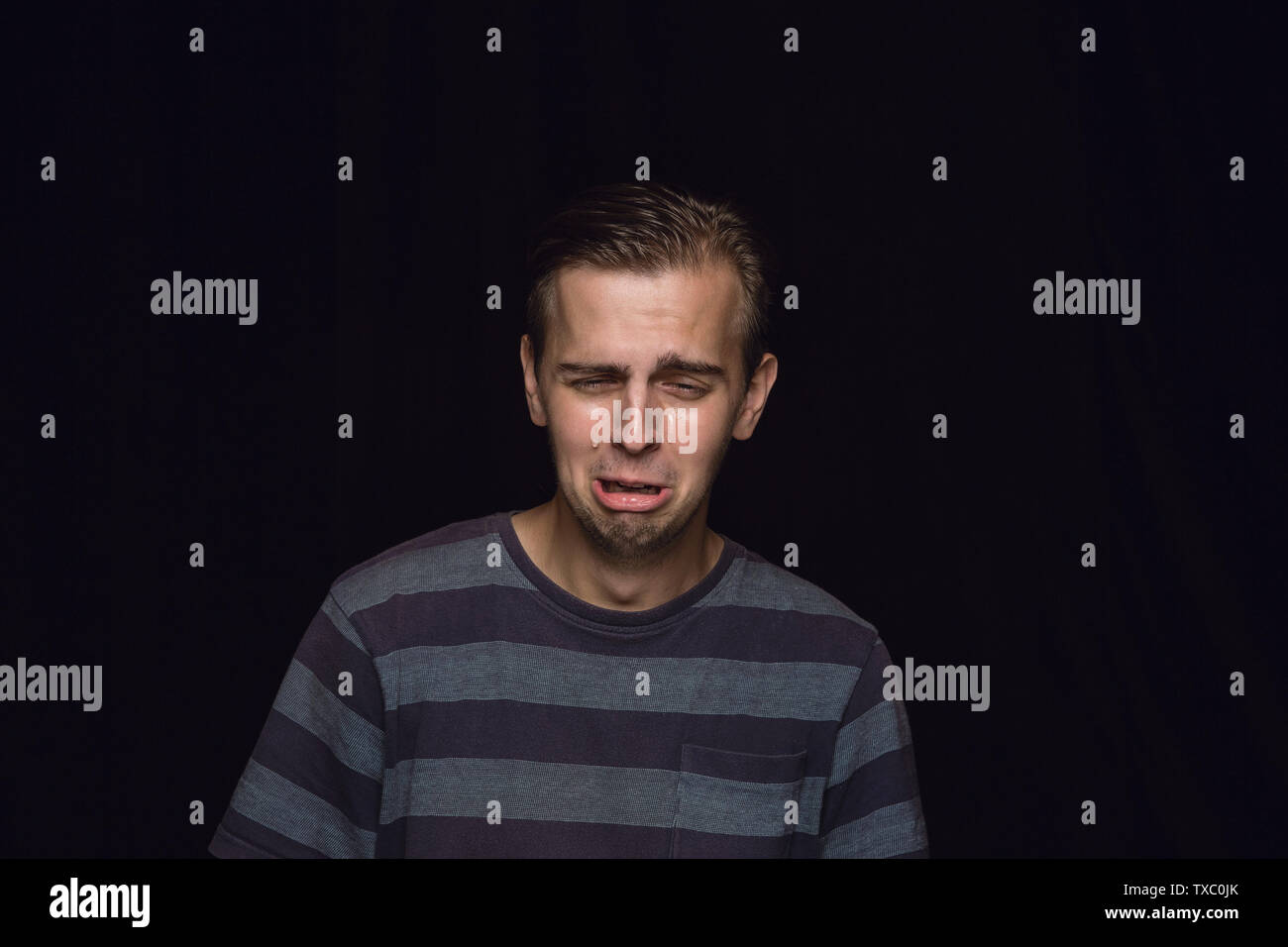 Close up portrait of young man isolated on black studio background ...