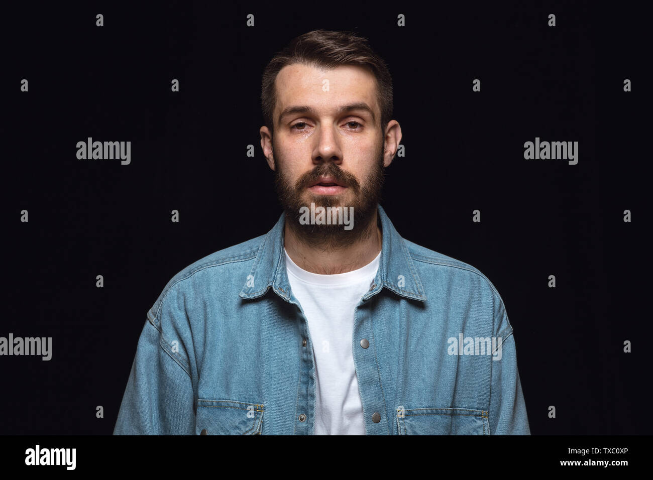 Close up portrait of young man isolated on black studio background ...