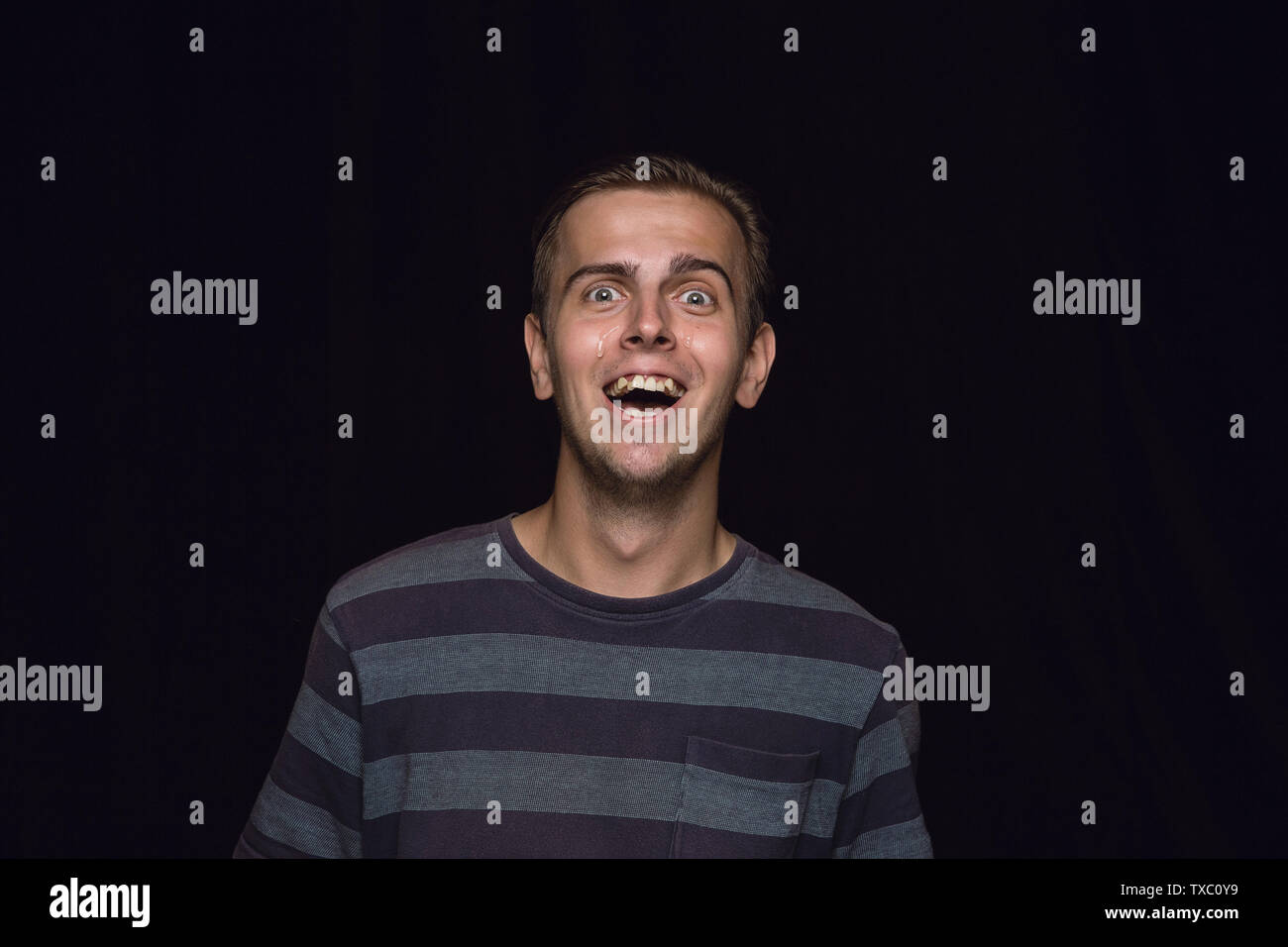 Close up portrait of young man isolated on black studio background ...