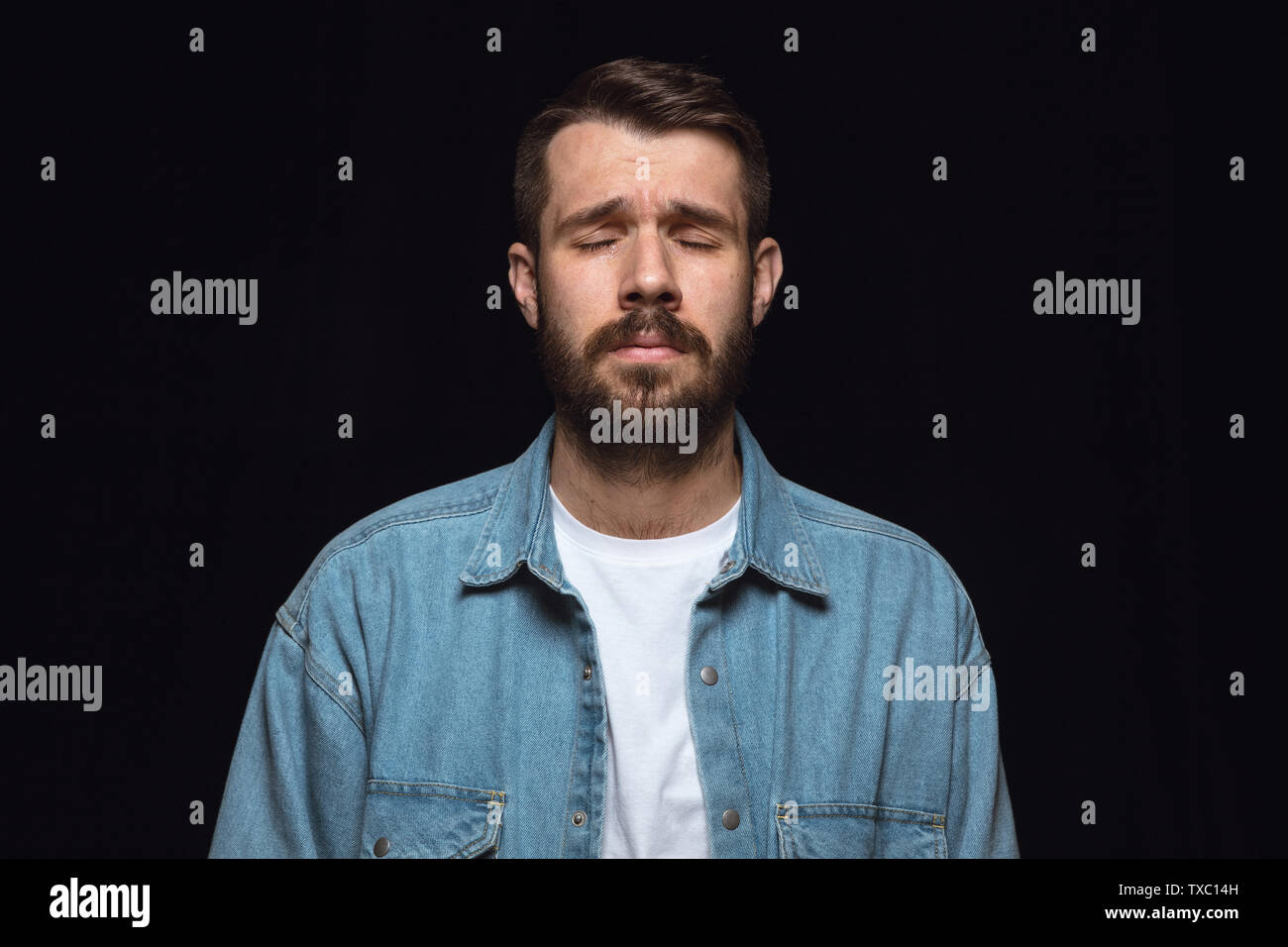 Close up portrait of young man isolated on black studio background ...
