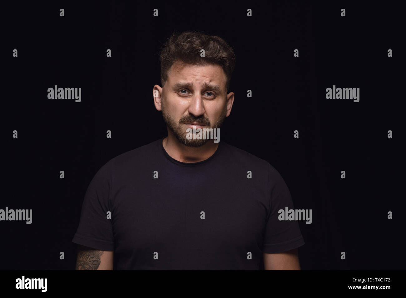 Close up portrait of young man isolated on black studio background ...