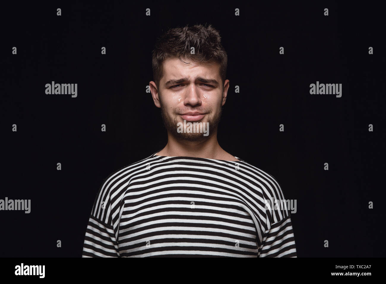 Close up portrait of young man isolated on black studio background ...