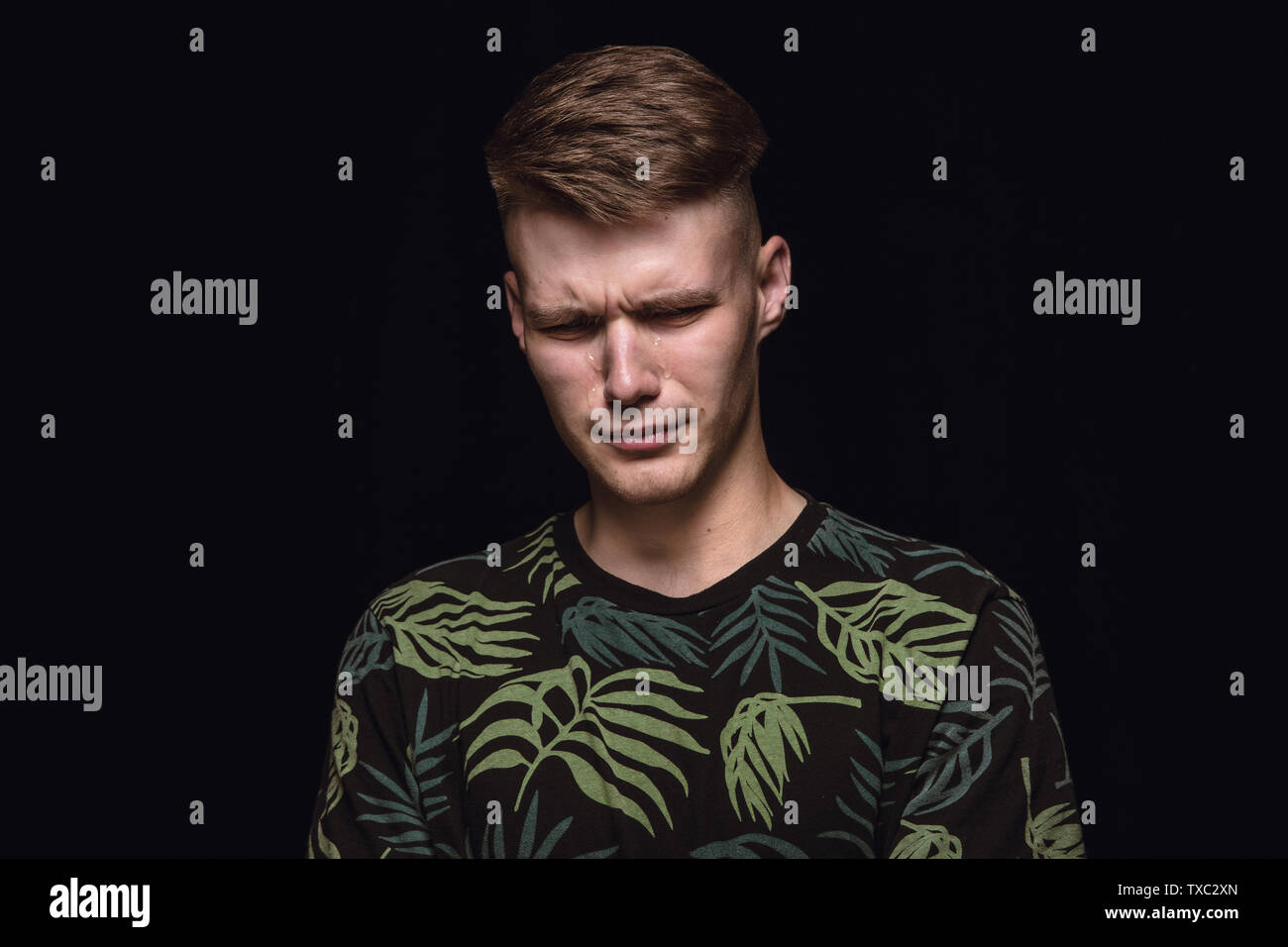 Close up portrait of young man isolated on black studio background ...