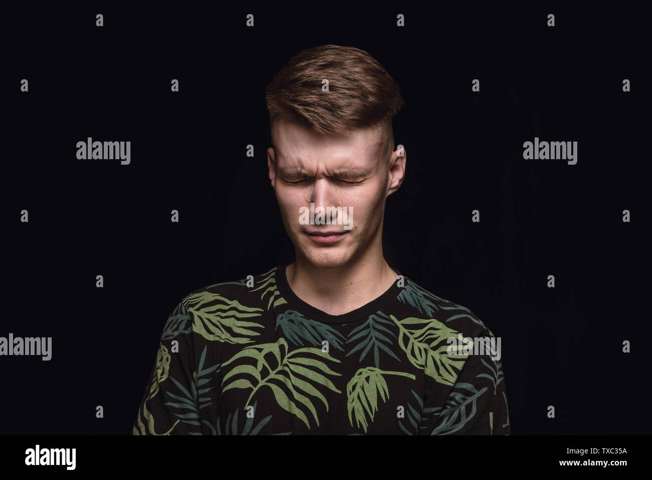 Close up portrait of young man isolated on black studio background ...