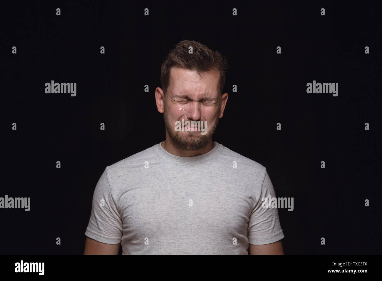 Close up portrait of young man isolated on black studio background ...