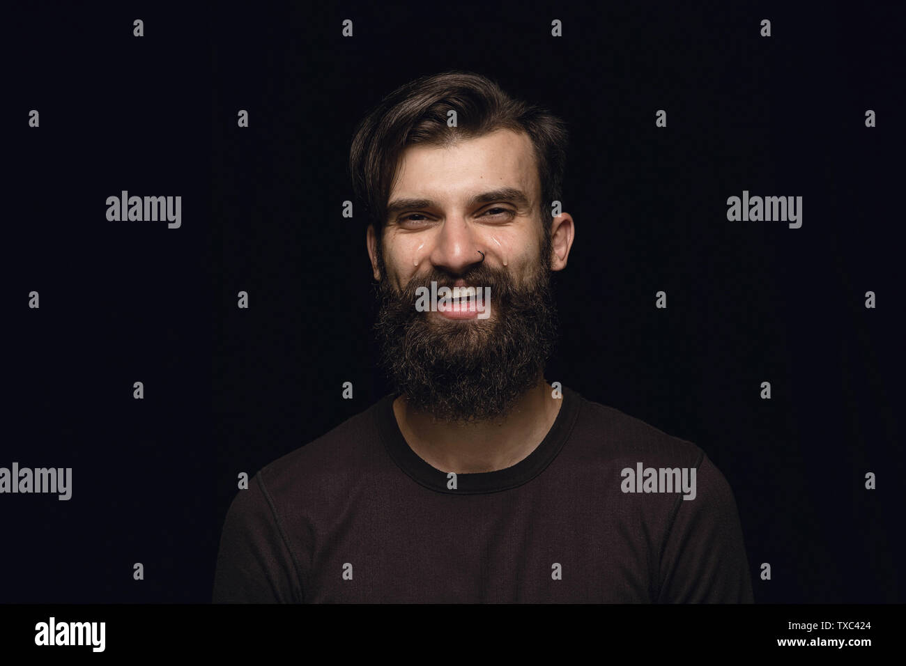 Close up portrait of young man isolated on black studio background ...