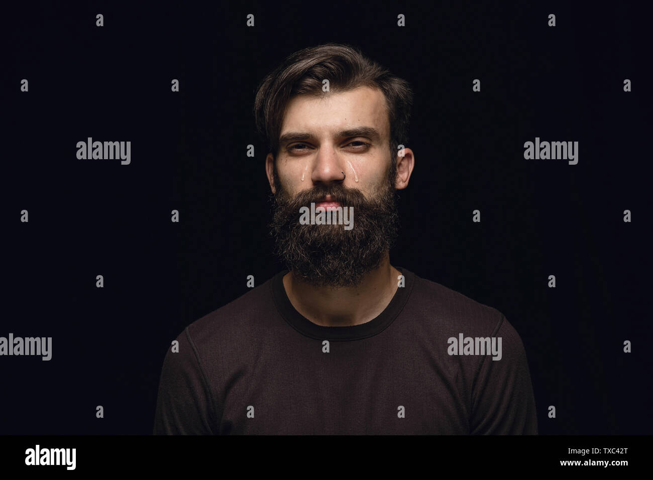 Close up portrait of young man isolated on black studio background ...