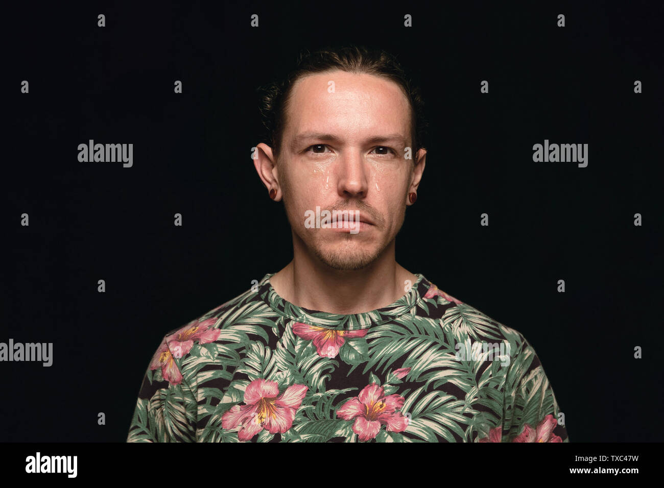Close up portrait of young man isolated on black studio background ...
