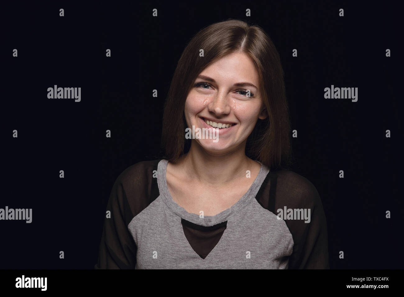 Close up portrait of young woman isolated on black studio background ...