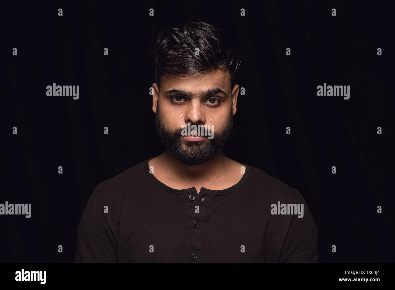Close up portrait of young man isolated on black studio background ...